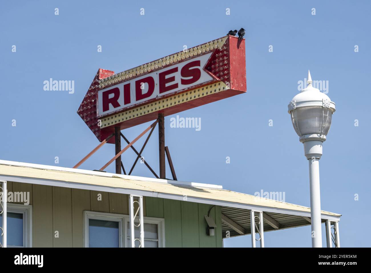 A red sign with arrow pointing at the boardwalk where carnival rides ...