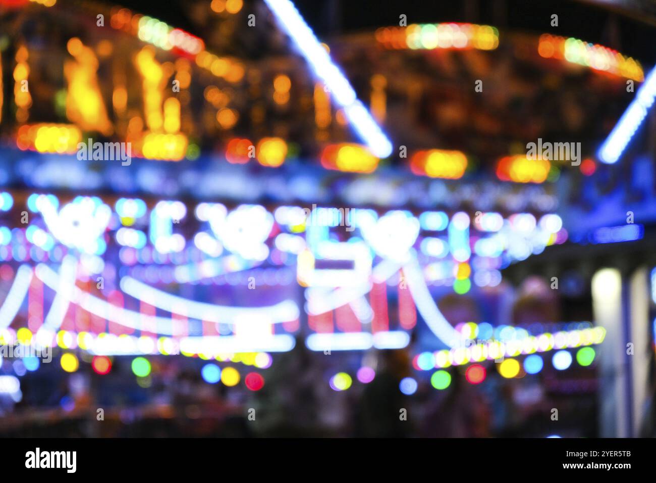 Defocused bright lights flash at a fun carnival at night. Amusement ...