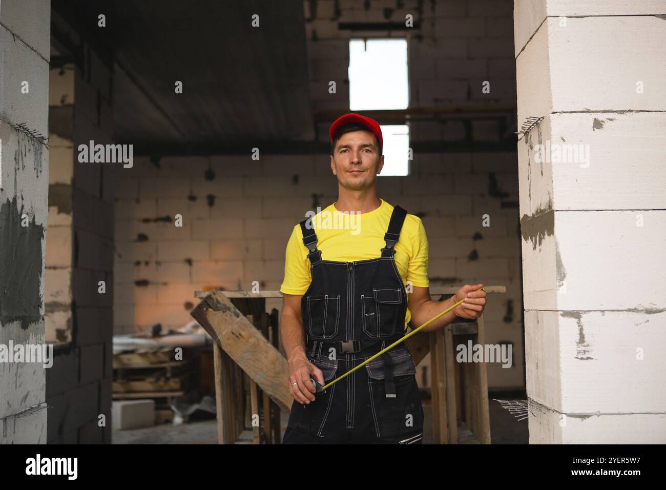 Construction worker engineer at construction site measures the length ...