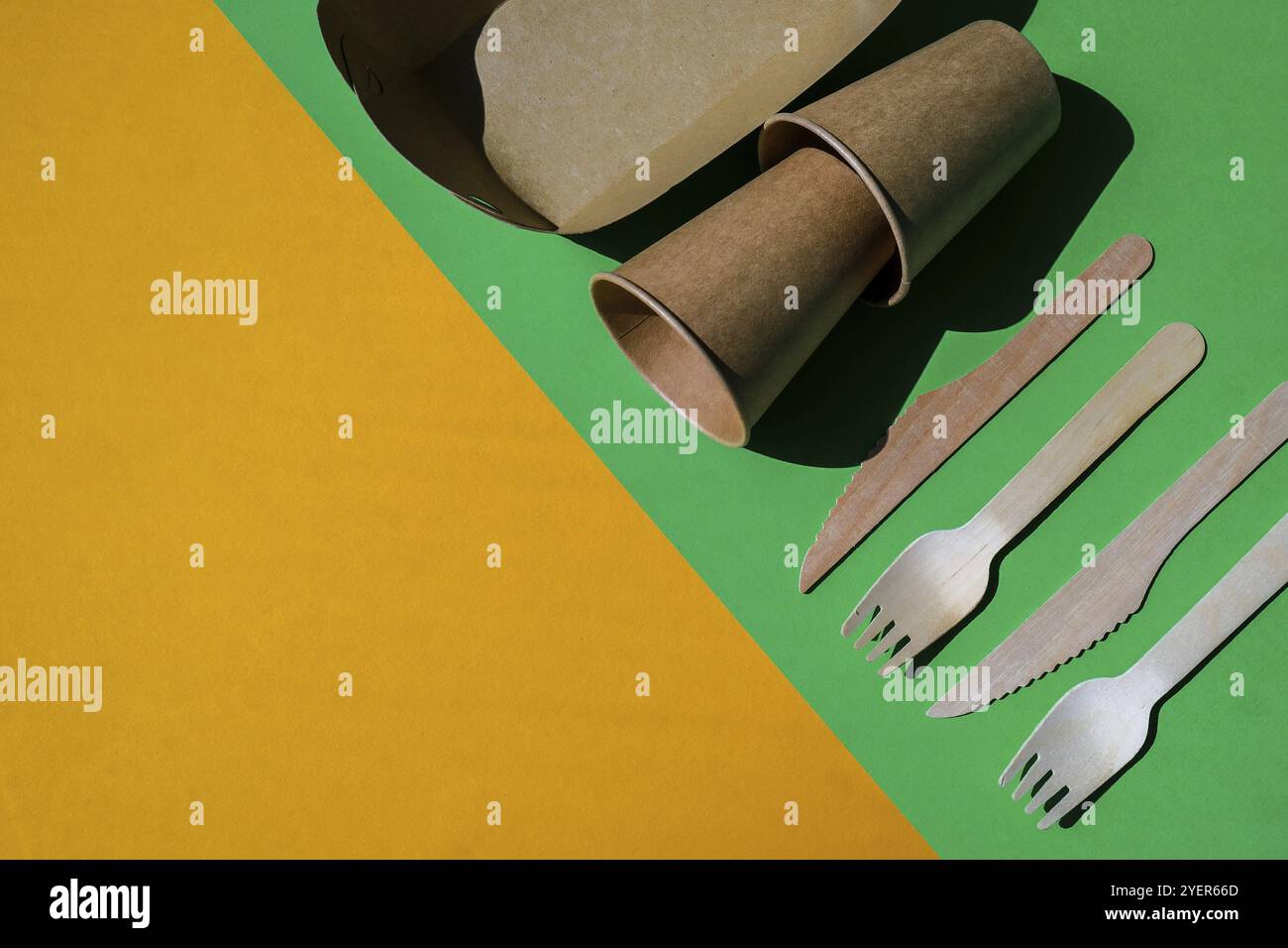 Wooden forks and paper cups with plates on color background. Eco ...