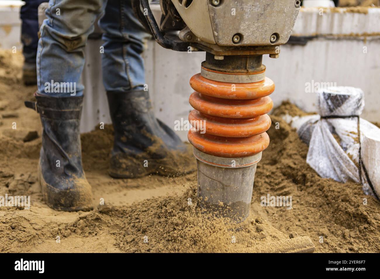 Closeup view of a person operating a vibratory earth rammer compacting ...