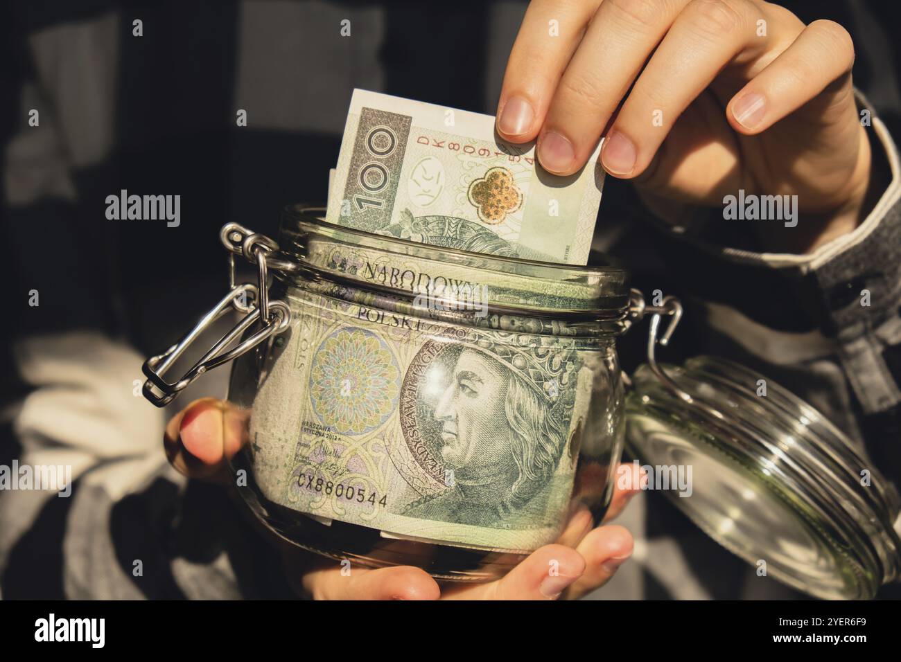 Polish zloty banknote saving money in glass jar. Unrecognizable woman ...