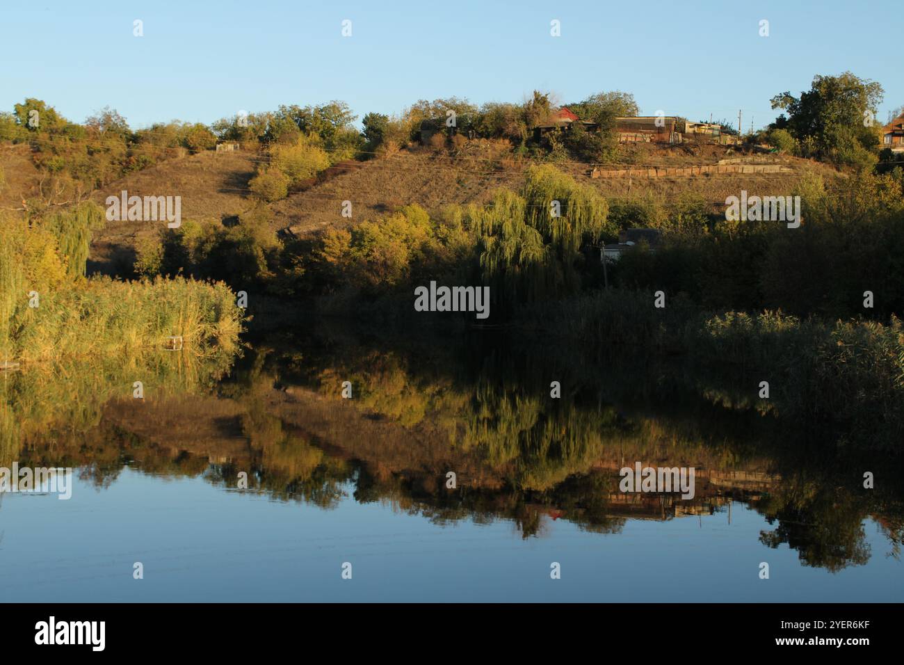 River with reflections of trees and a hill, creating a double landscape ...