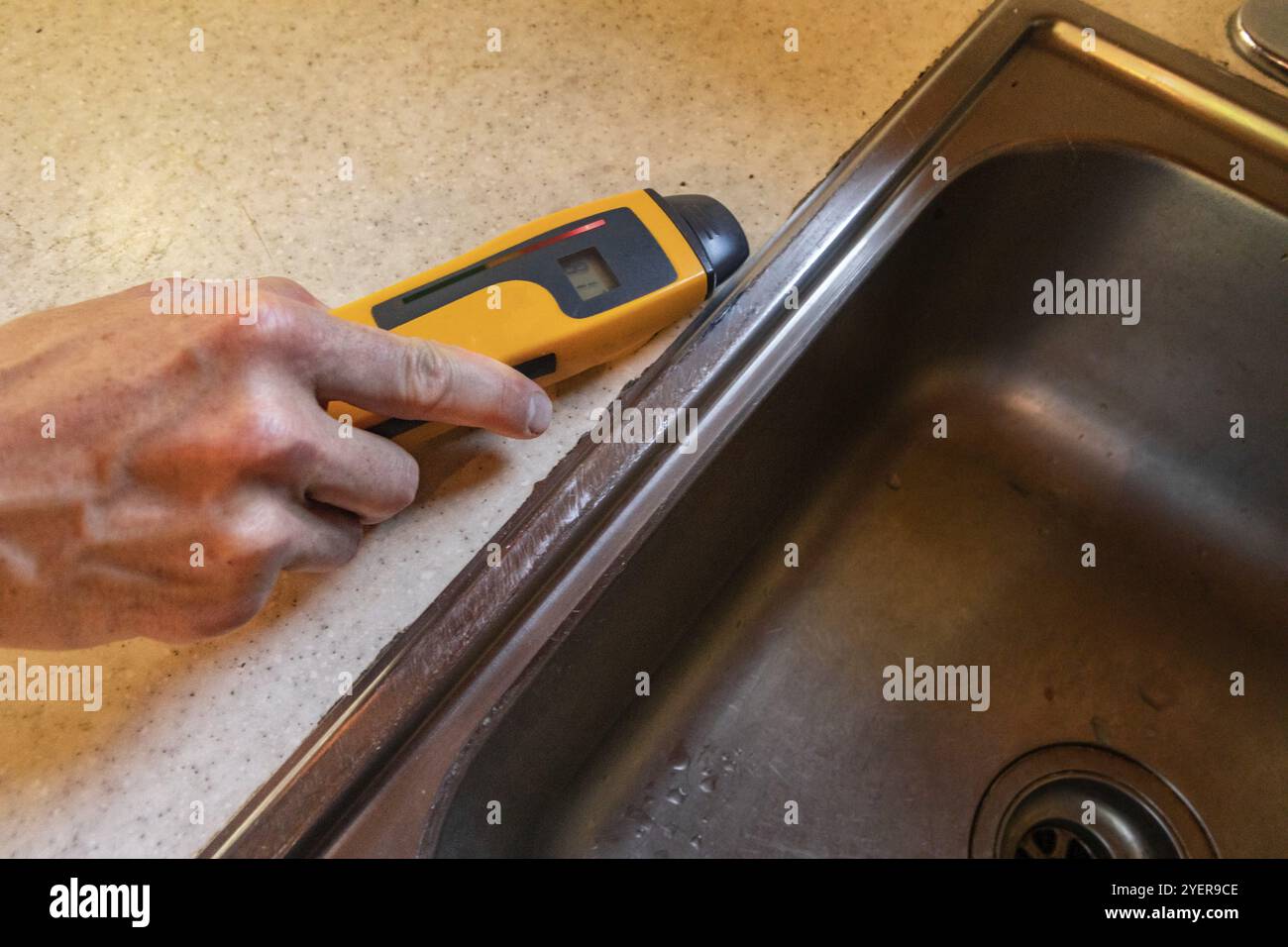 A close up view of a man holding an electronic moisture meter, showing ...
