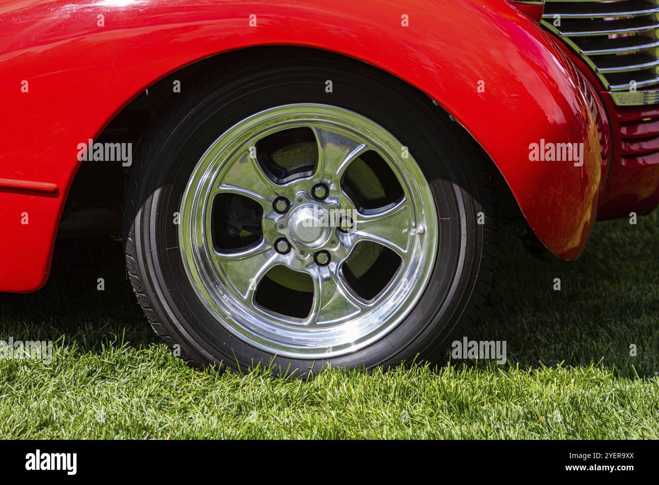 Old classic American bright red car wheel on the grass, chrome star rim ...