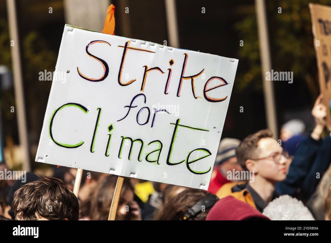 A cardboard placard is seen close-up on a crowded street of ...