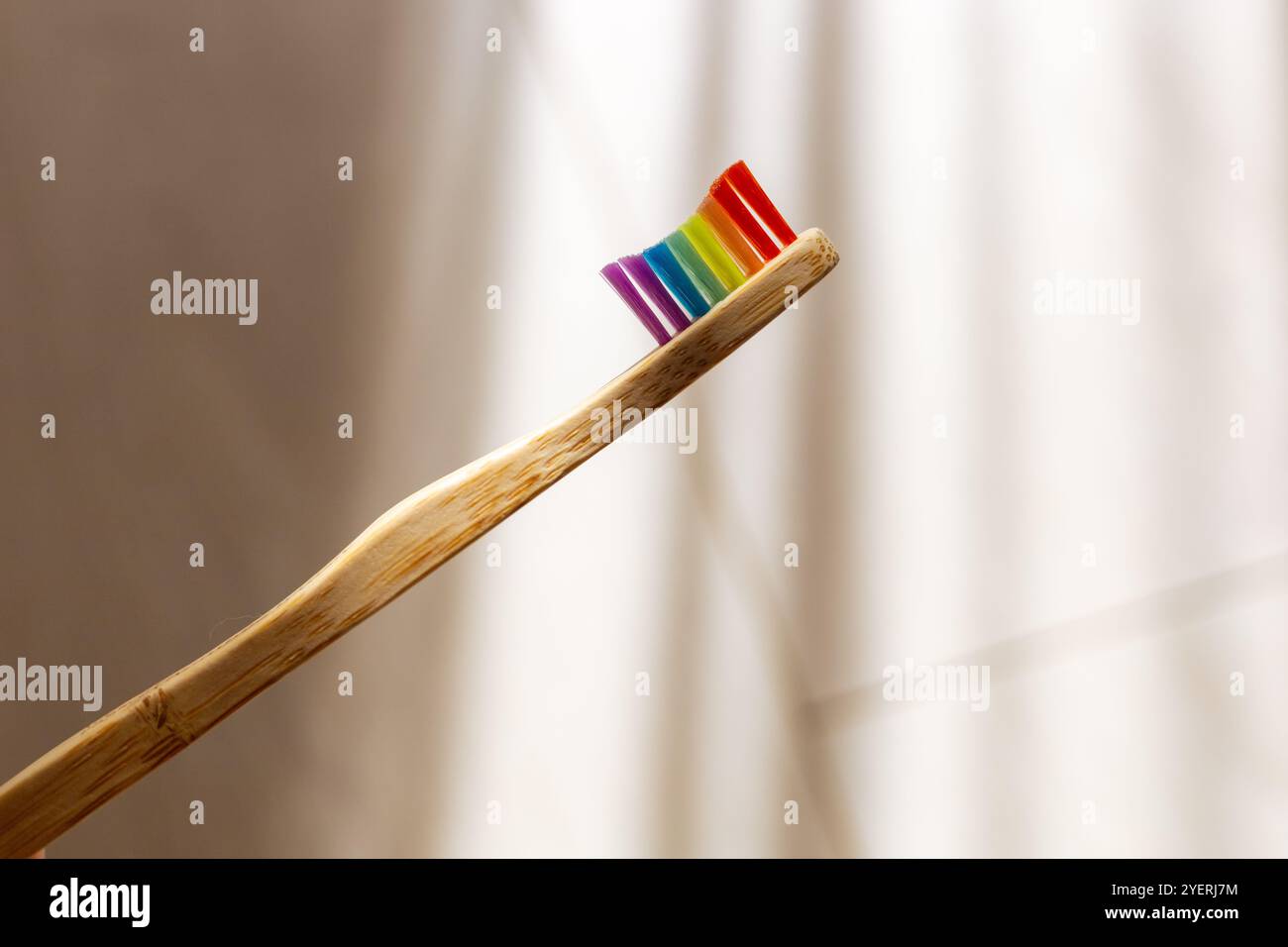 A wooden toothbrush features vibrant rainbow bristles, illuminated by ...