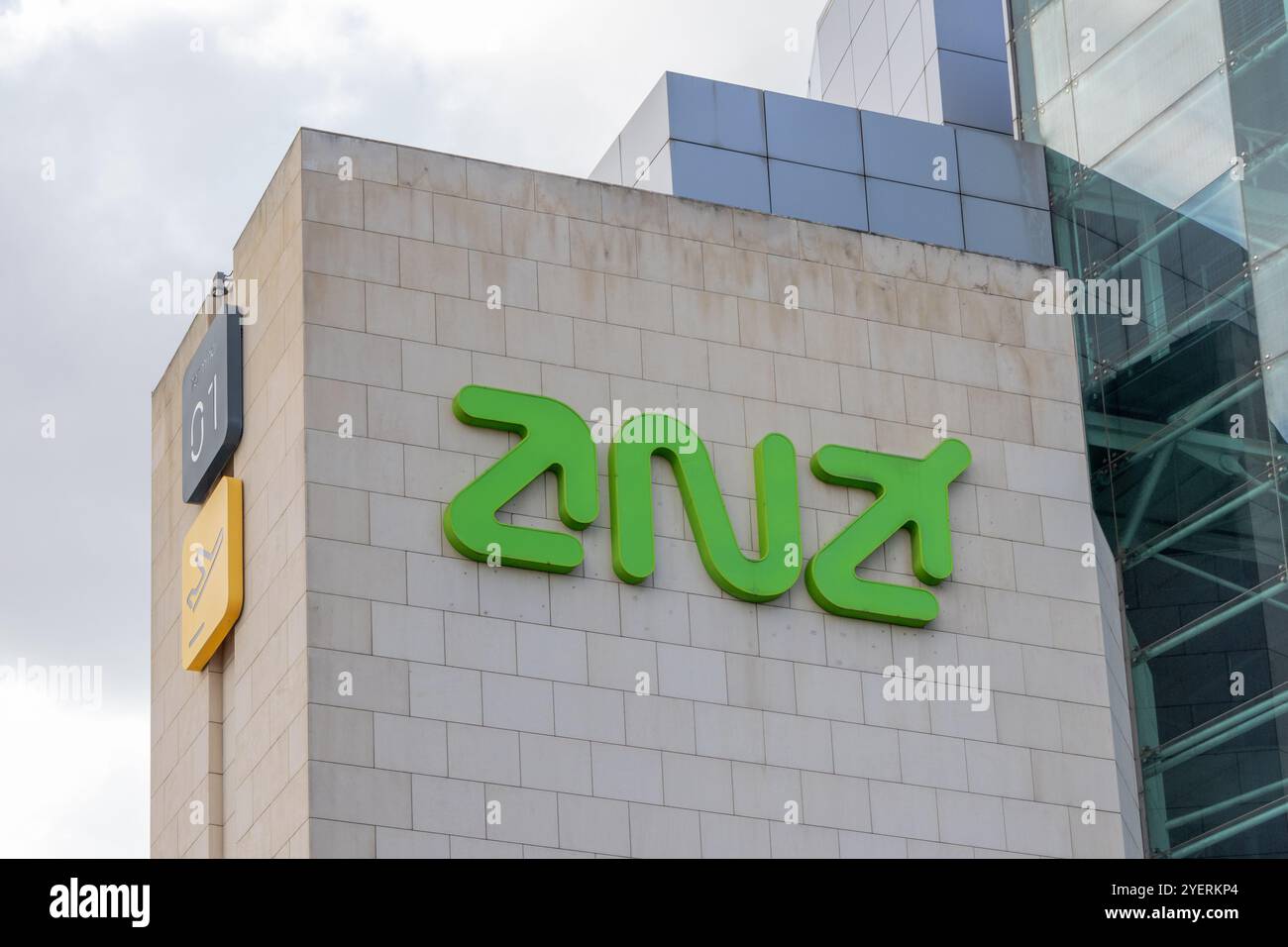 Green anz bank logo with an arrow pointing right, mounted on a tiled ...