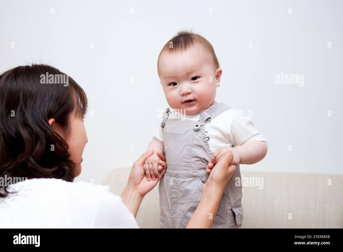 Baby standing up holding on to mother Stock Photo - Alamy