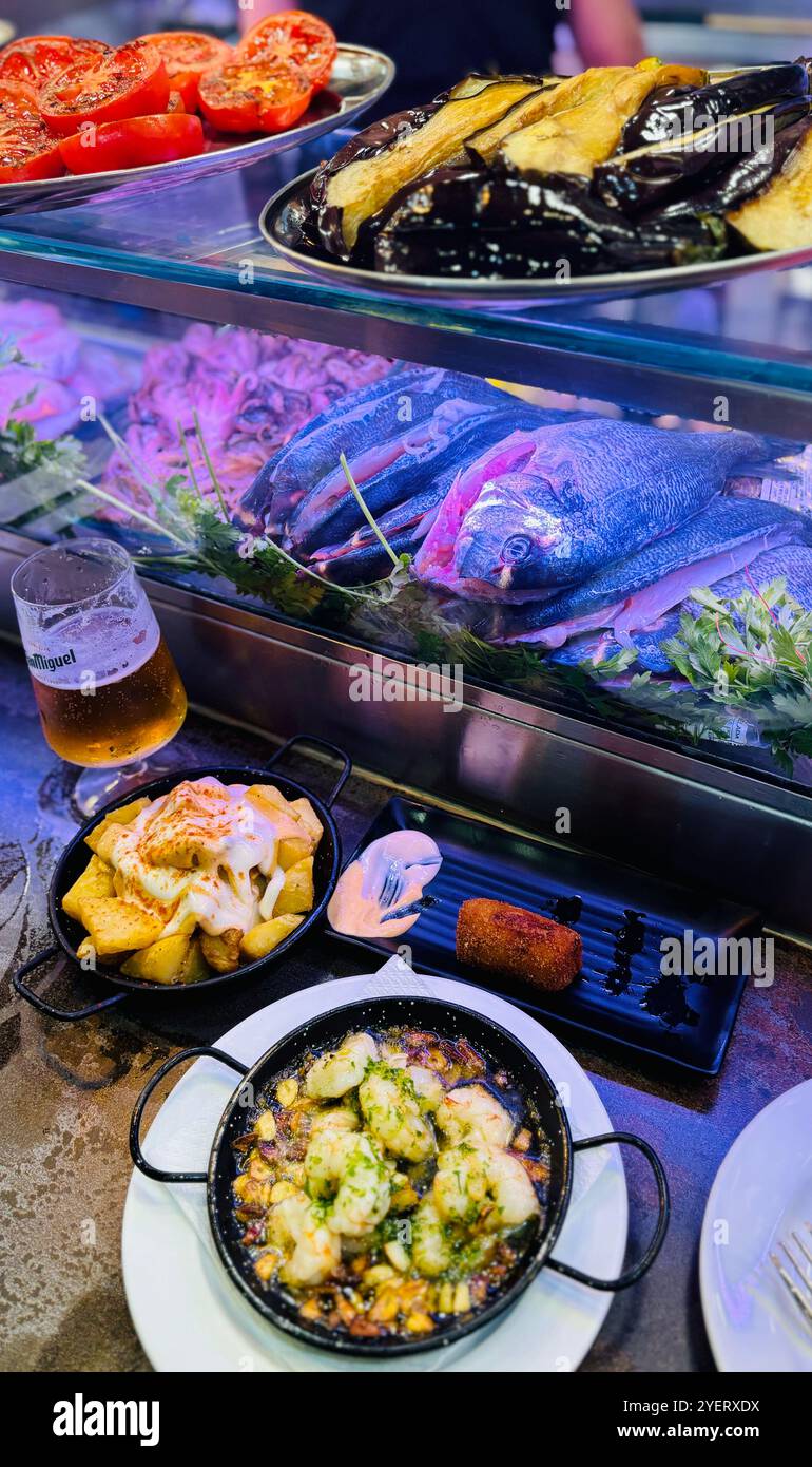 San Miguel draft beer with papatas bravas and grilled squid at a Tapas ...