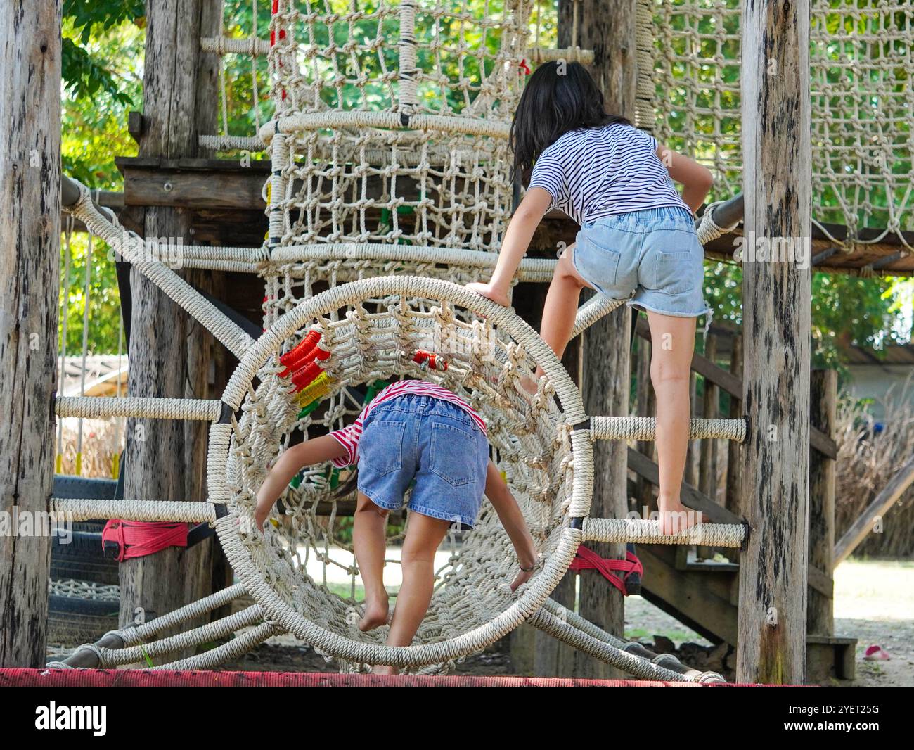 Children play outdoors on a wooden playground in a park. Happy girl ...