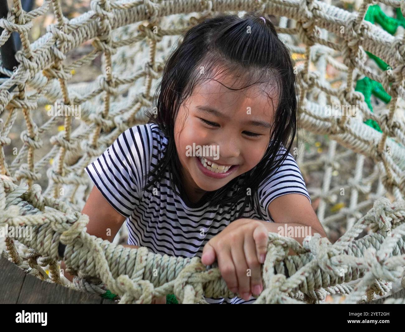 Children play outdoors on a wooden playground in a park. Happy girl ...