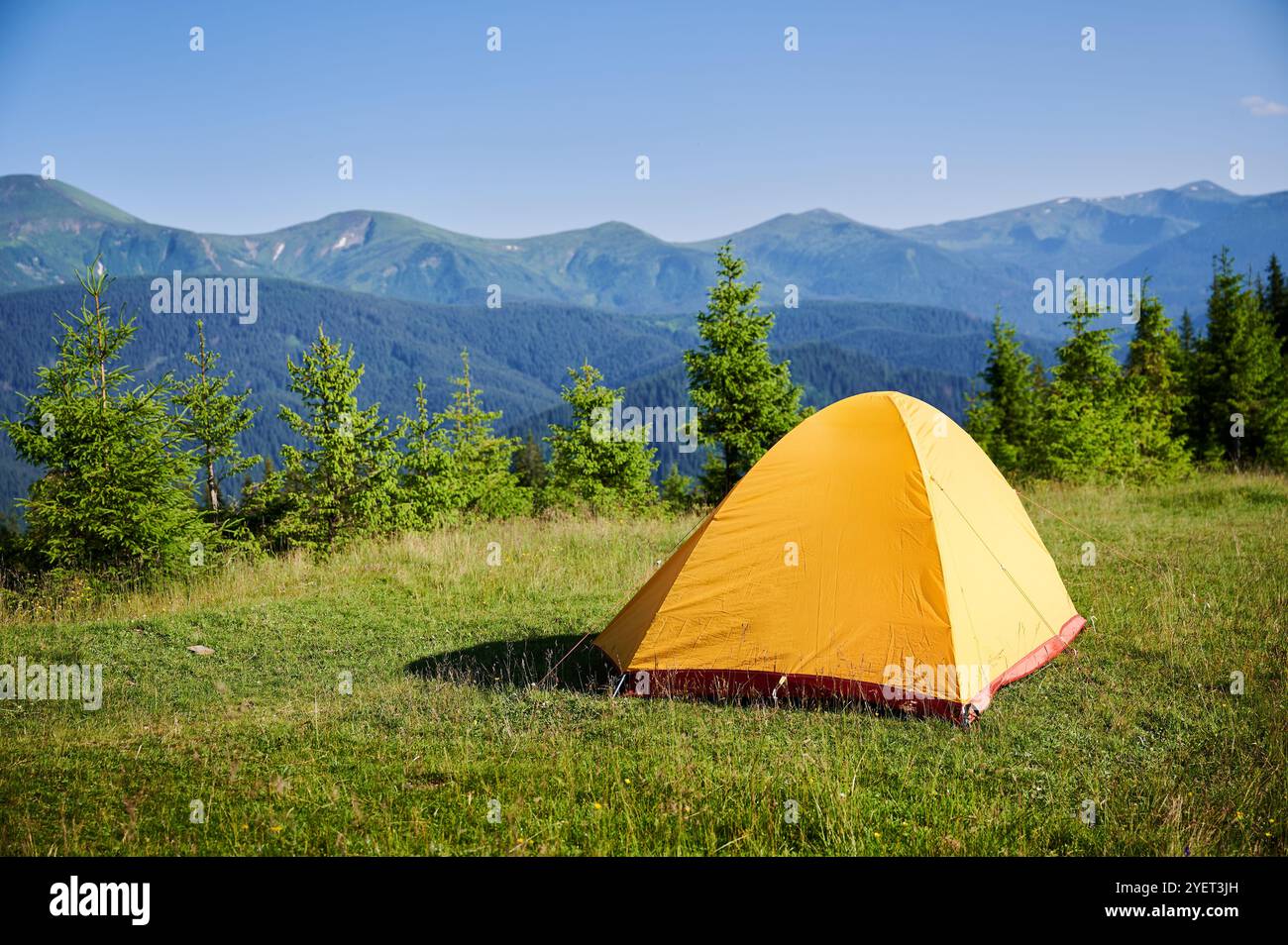 Bright yellow tent on grassy hillside, overlooking breathtaking ...