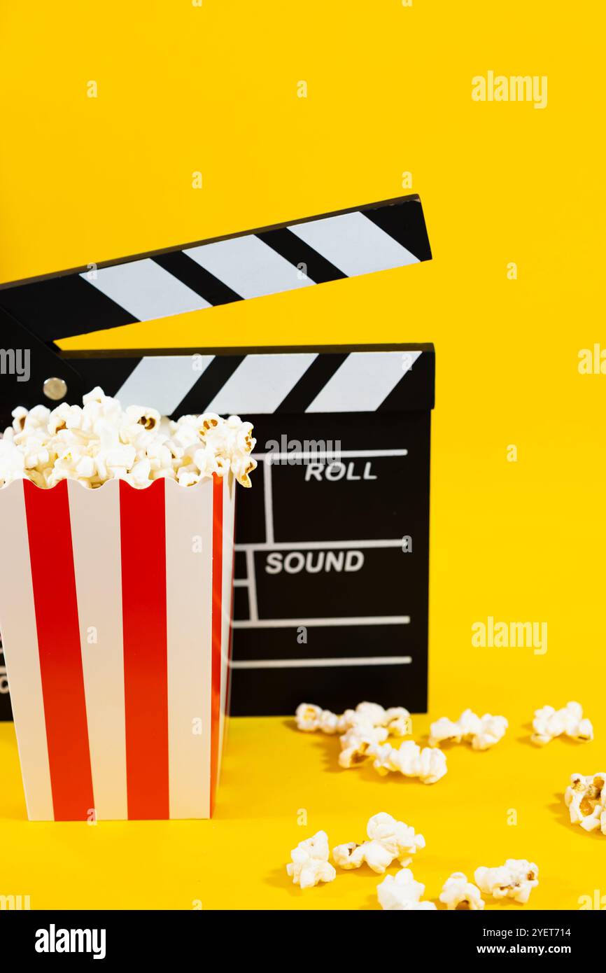 Vertical image of popcorn with wooden movie clapperboard on a yellow ...
