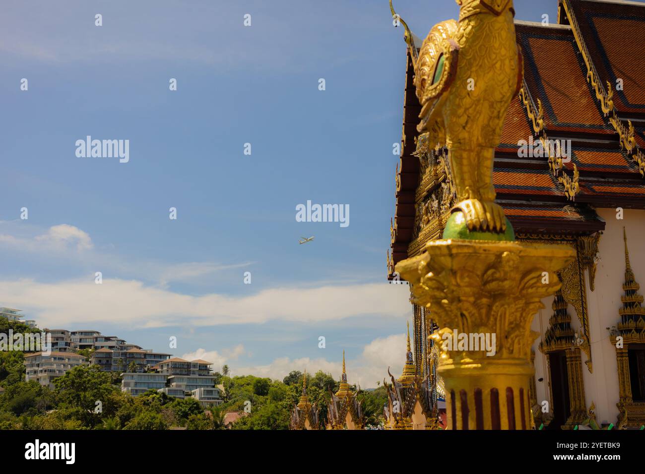 Golden statue of a mythical bird with a traditional Thai temple in the ...