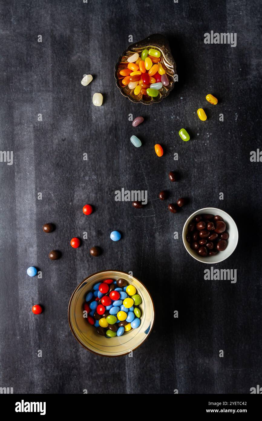 Two bowls of colorful sweet candies on black chalkboard background ...