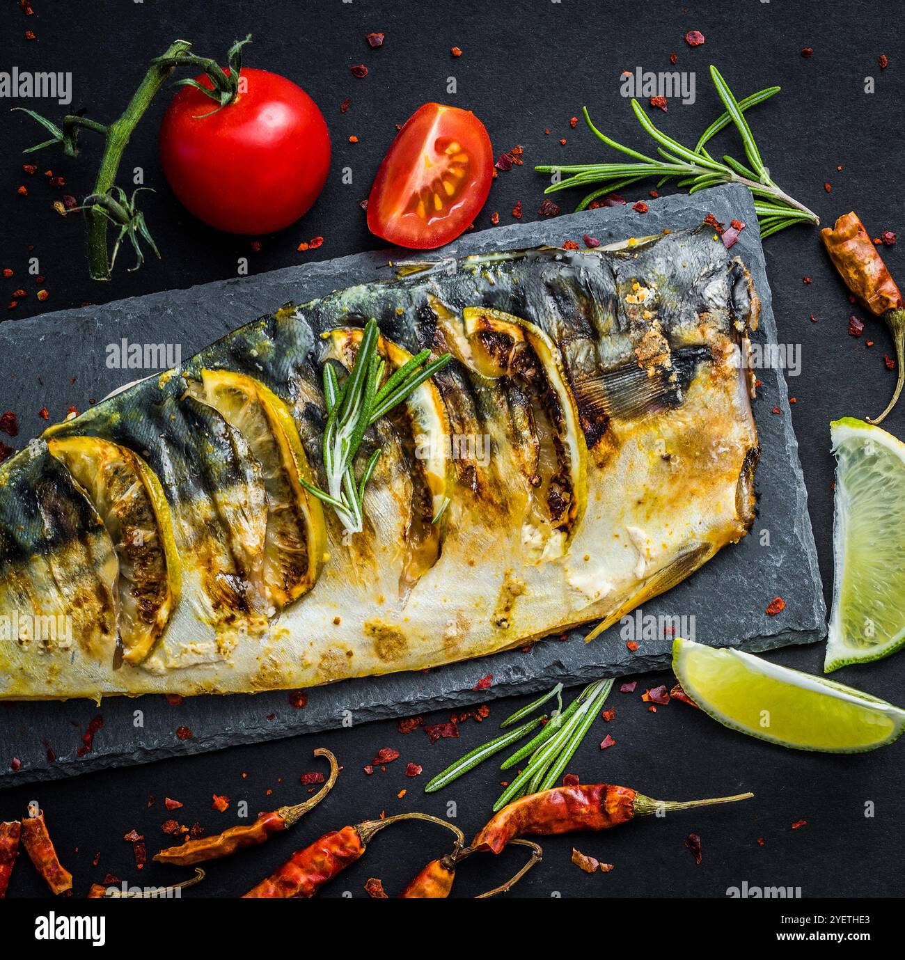 Grilled mackerel fillets with lime on black slate board, fish with ...