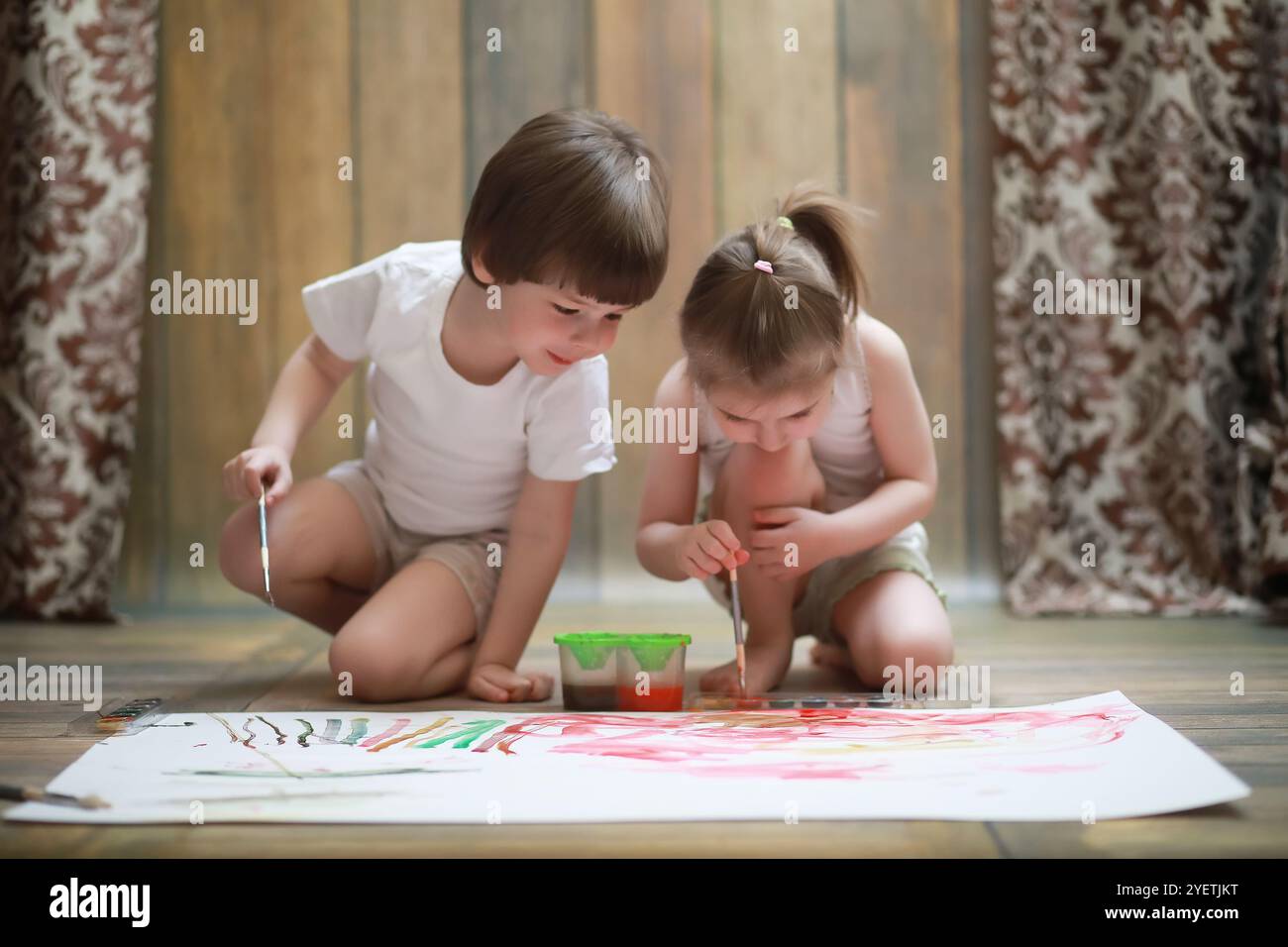Little children paint on a large sheet of paper on the floor Stock ...