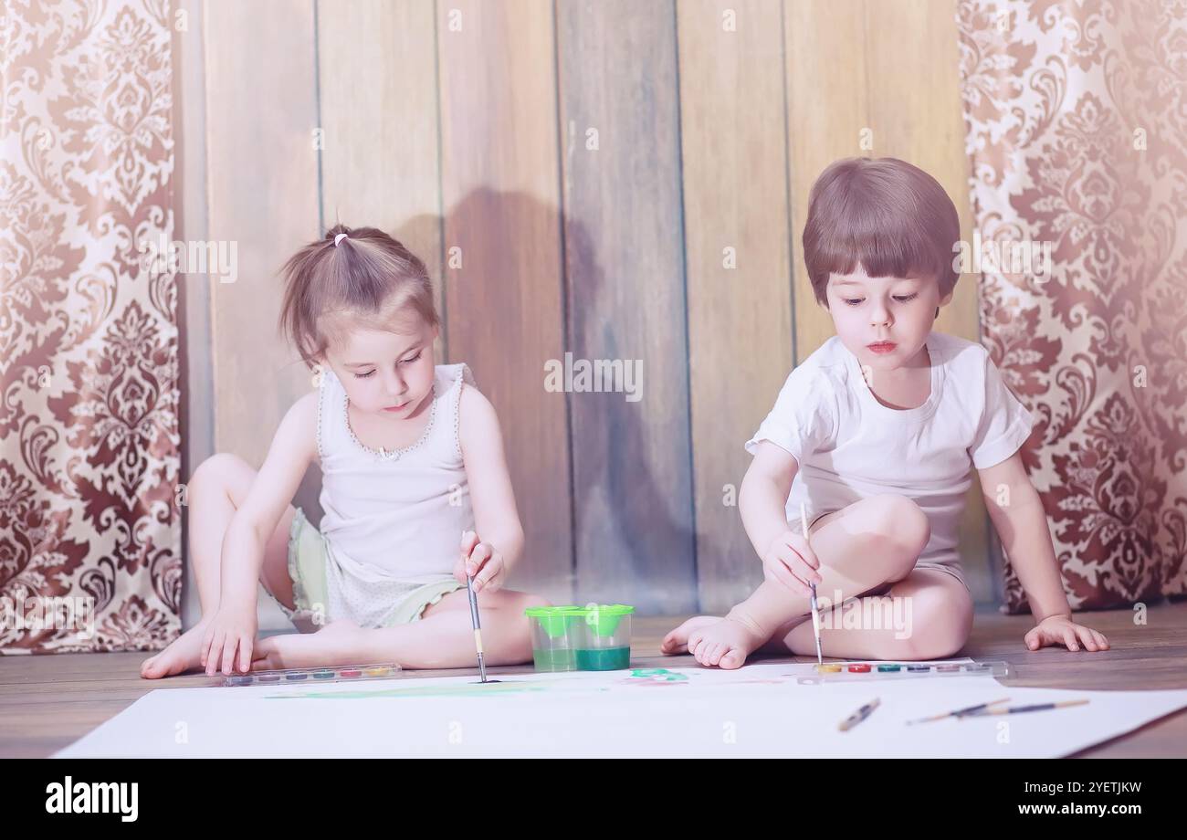 Little children paint on a large sheet of paper on the floor Stock ...