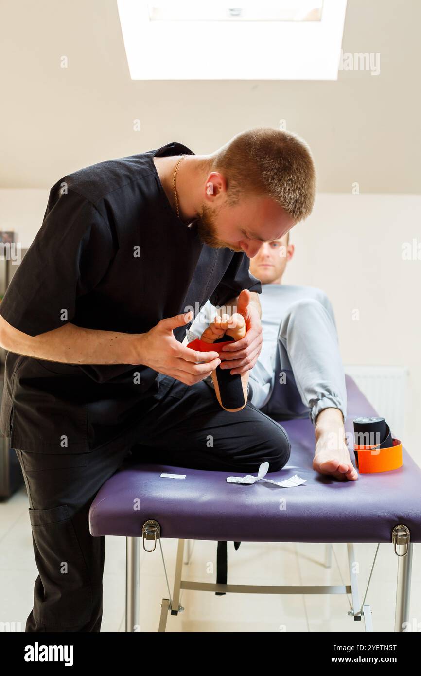 Male physiotherapist doctor massages the feet of a relaxed man sitting ...