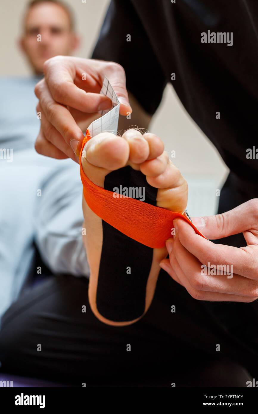 Male physiotherapist doctor massages the feet of a relaxed man sitting ...