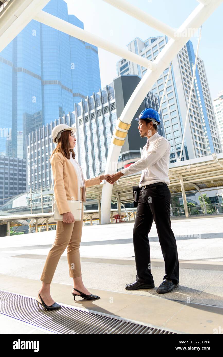 Civil Construction engineer teams shaking hands together wear work helmets worker on ...