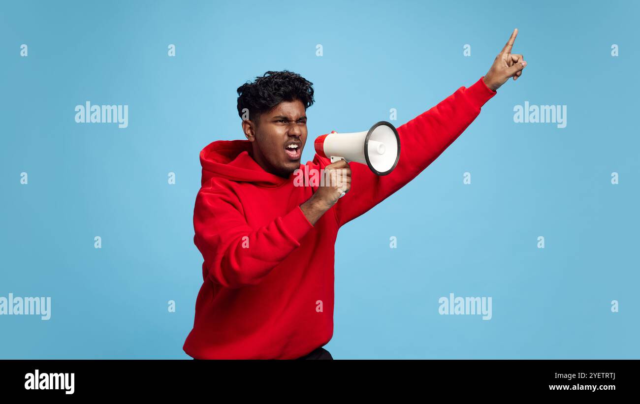 Emotional young Indian man shouting in megaphone wand lively gesturing ...