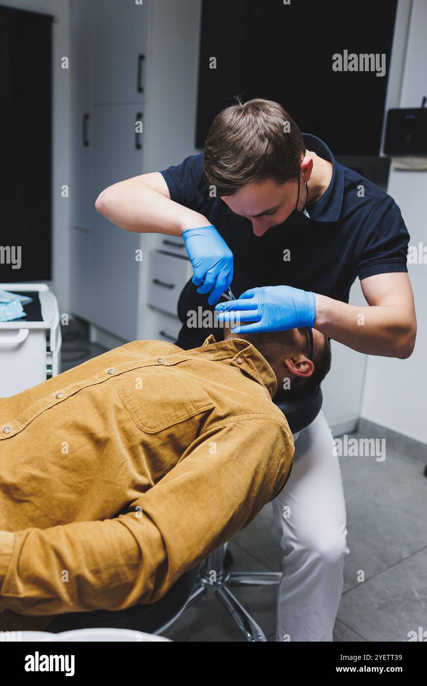 An orthodontist treats the teeth of his patient in a modern, bright ...