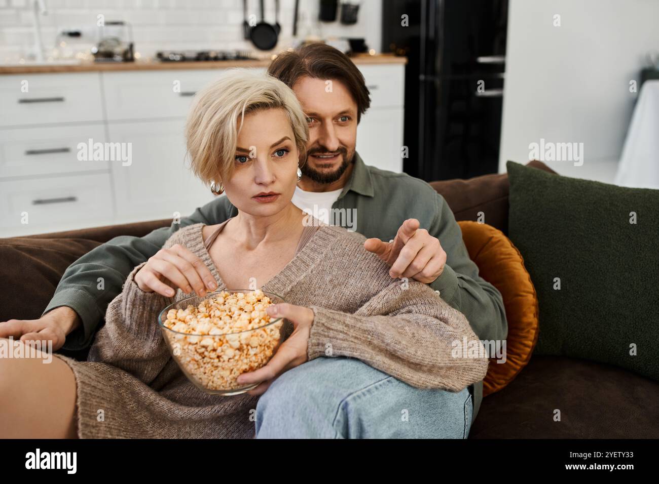 A couple shares a tender moment on the couch, enjoying popcorn and a ...