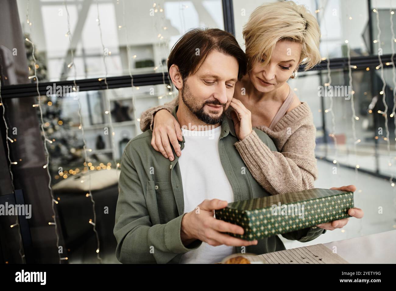 A man enjoys a surprise gift from his partner in a warm, intimate ...