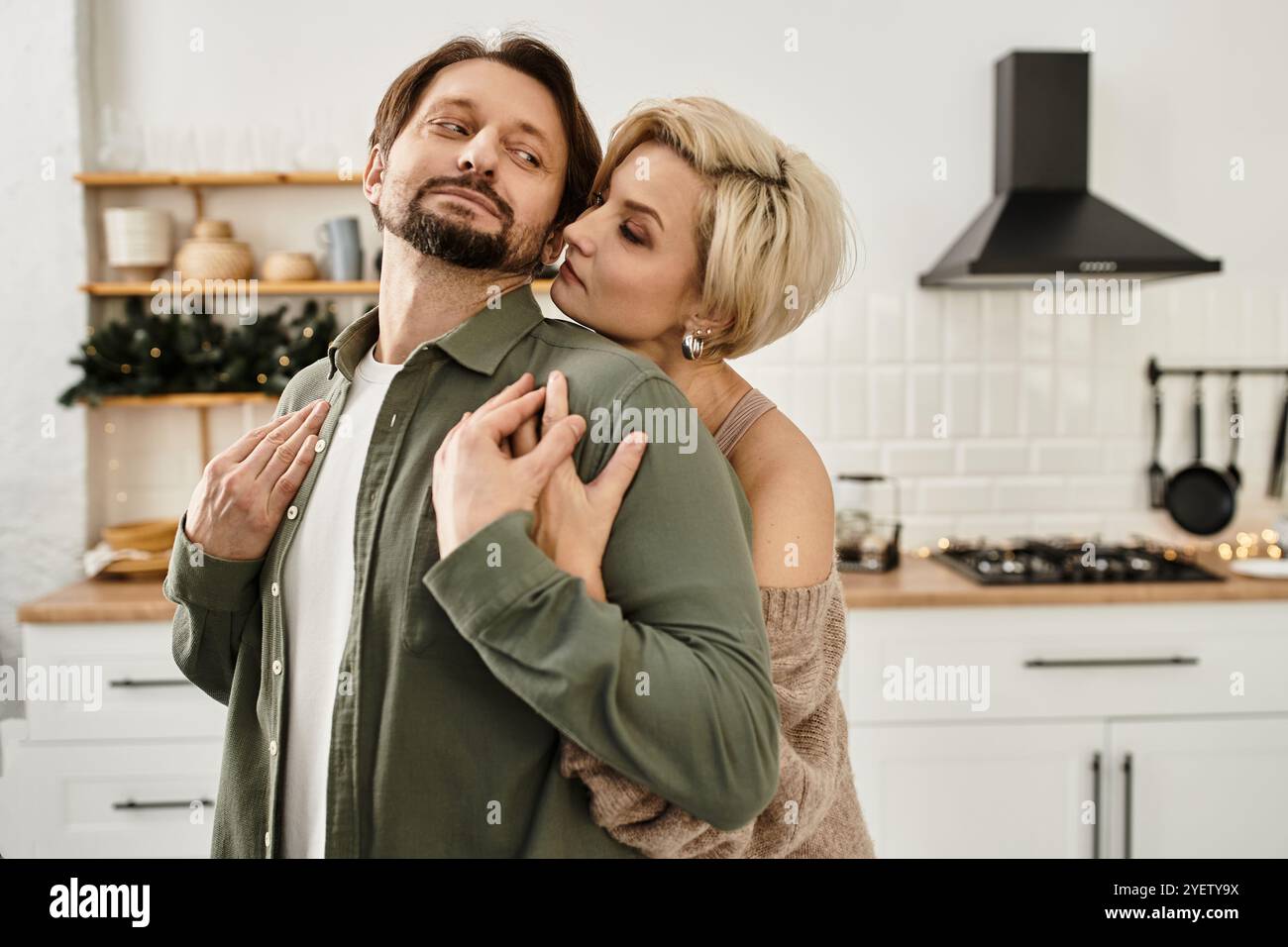 The couple shares a warm embrace in their inviting kitchen, radiating ...