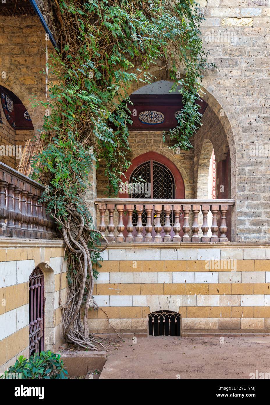 Historic courtyard with arches, balconies, and ornate details. A vine ...