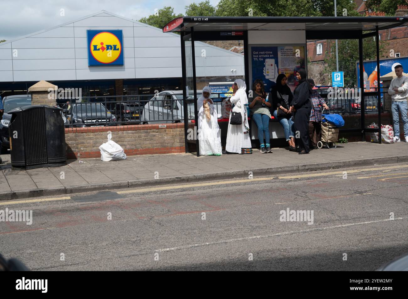 London, Hackney. Waiting at the bus stop in front of Lidl supermarket ...
