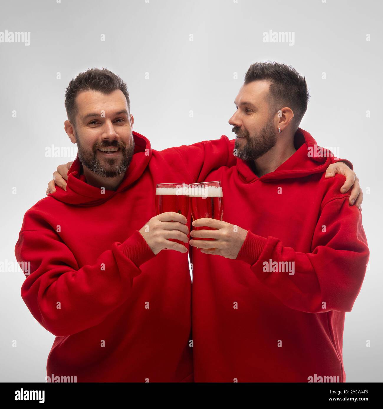 Portrait of two brothers, dressed matching outfits hugs and clinking ...