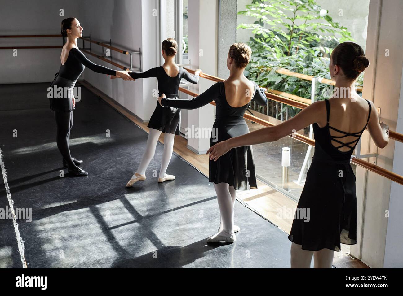 Rear view of three young girls wearing elegant dance leotards learning ...