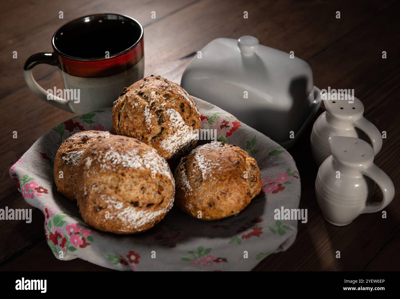 Classic farm country bread buns in a cute basket next to a mug, butter ...