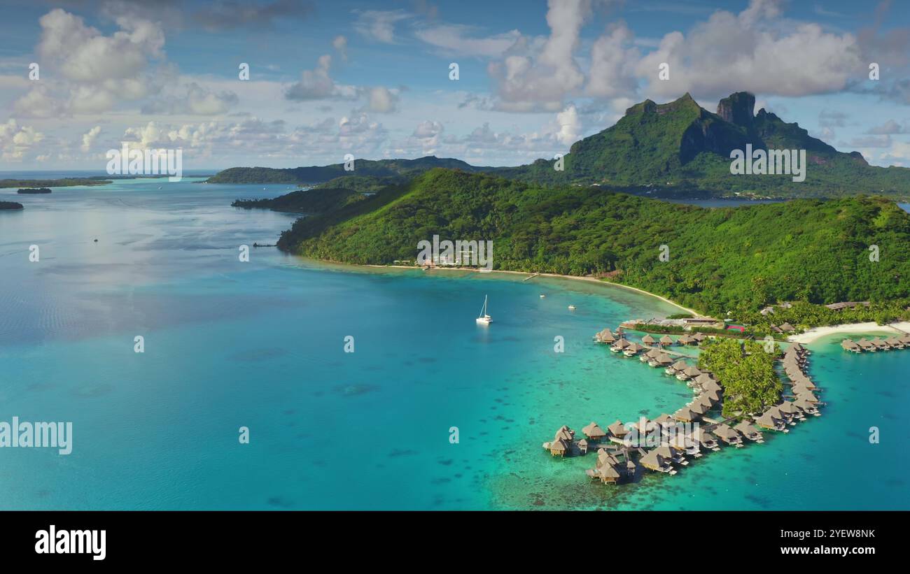 Turquoise lagoon water, overwater bungalows and green hills mountains ...