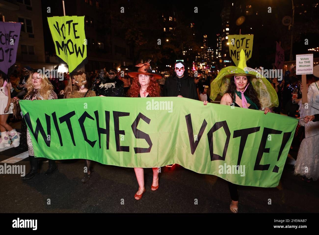 A group of women dressed as witches carrying a banner and signs march ...