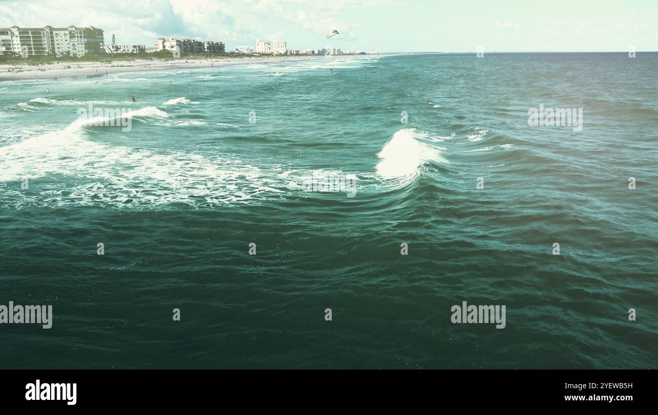 A view of ocean waves and tides, with water craft sports along a resort ...