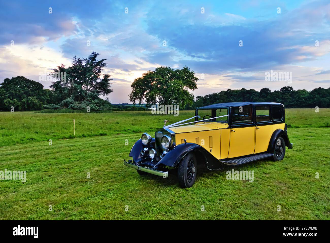 Yellow 1930s Rolls Royce Phantom II parked in grassy field at a wedding ...