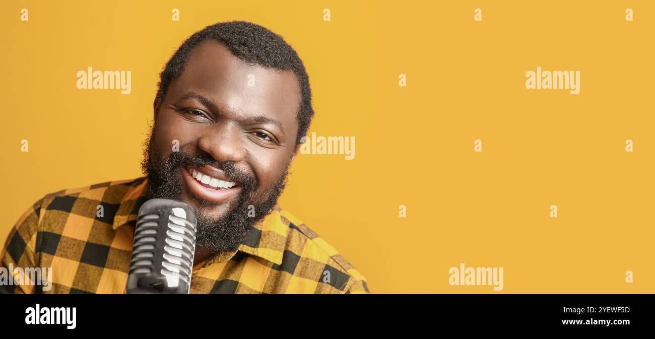 Male African-American singer with microphone on orange background with ...