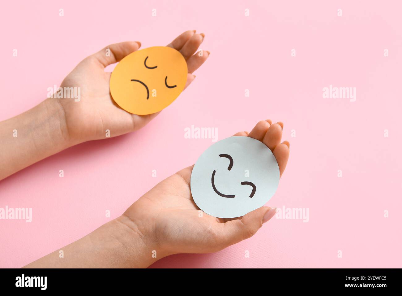 Female hands and paper faces with different emotions on pink background ...