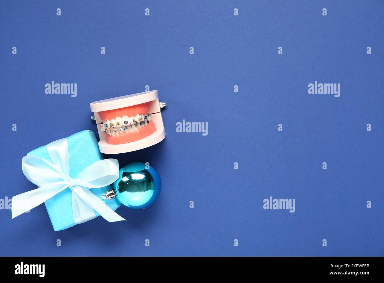 Model of jaw with dental braces, Christmas gift and ball on blue ...