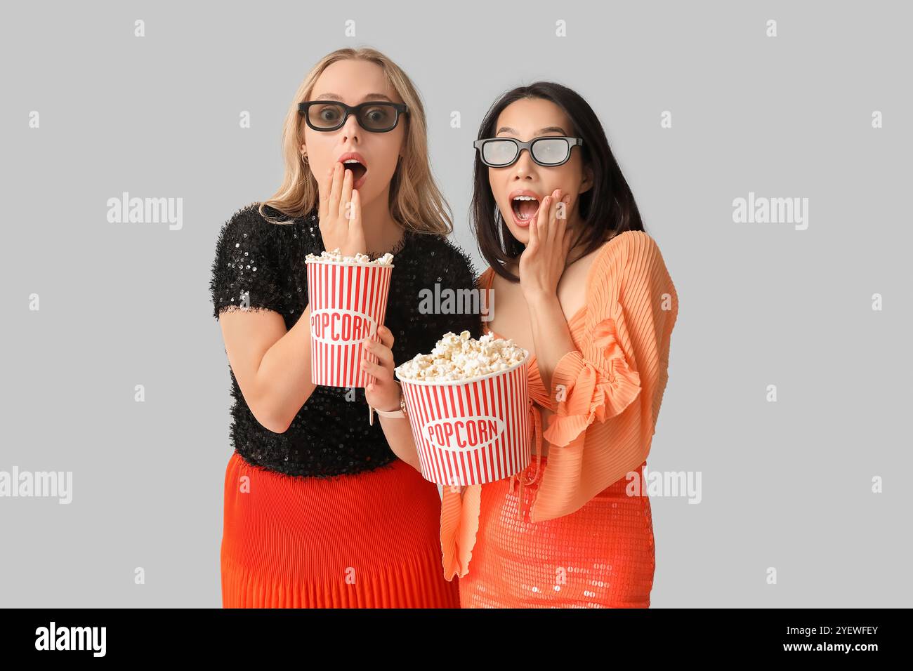 Emotional young women in 3D glasses with buckets of popcorn on white background Stock Photo - Alamy