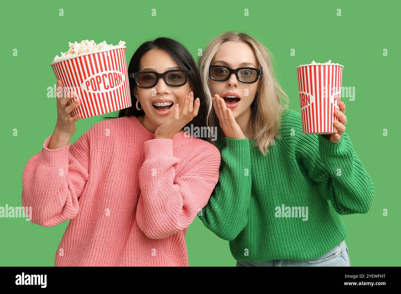 Emotional young women in 3D glasses with buckets of popcorn on green background Stock Photo - Alamy