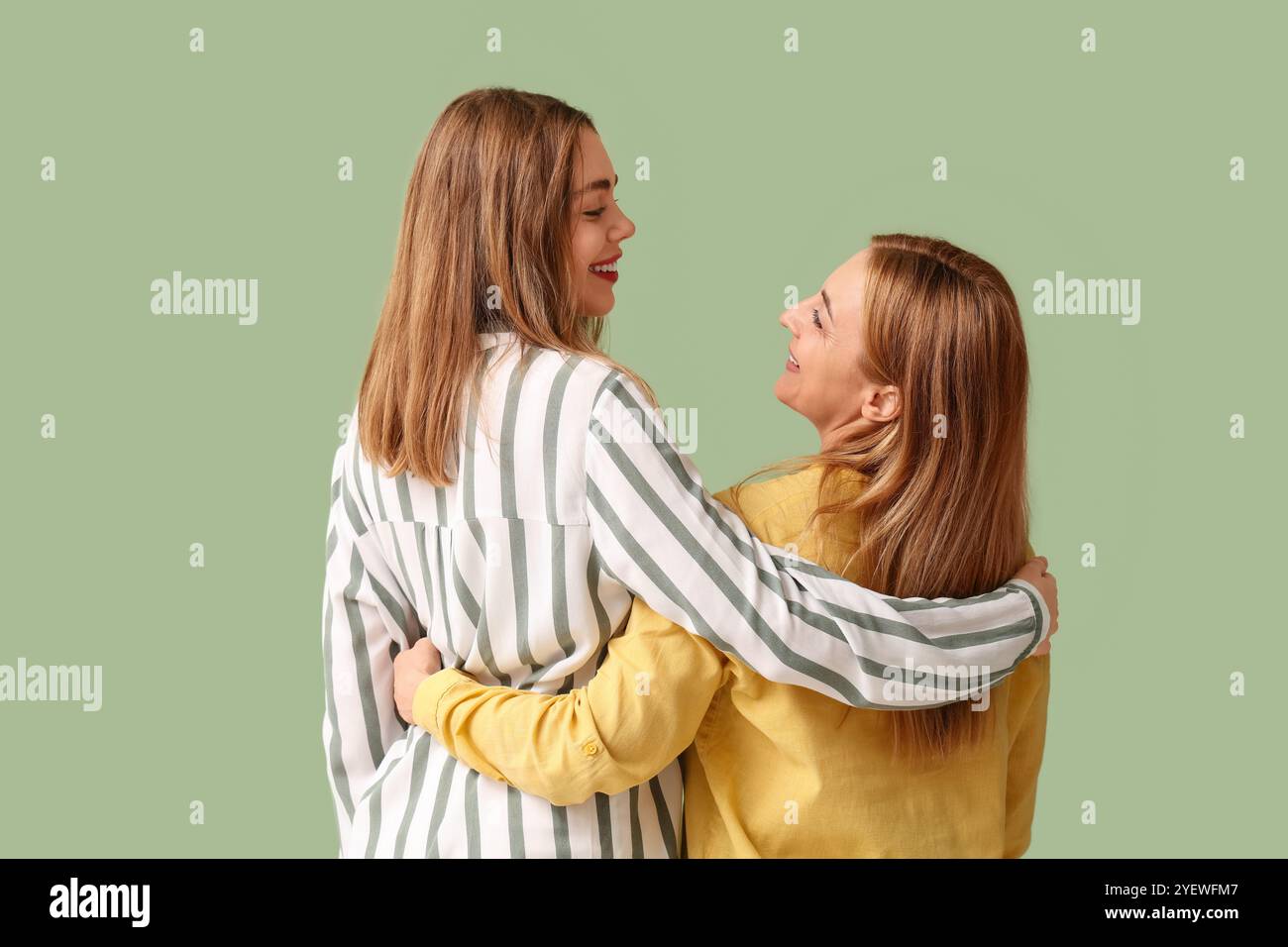 Beautiful young woman hugging her mother on green background ...