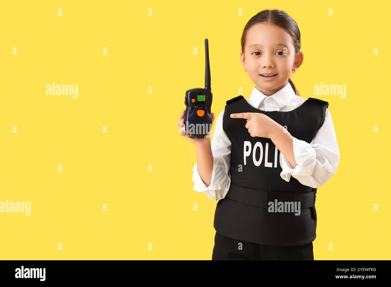 Cute little police officer pointing at radio transmitter on yellow ...