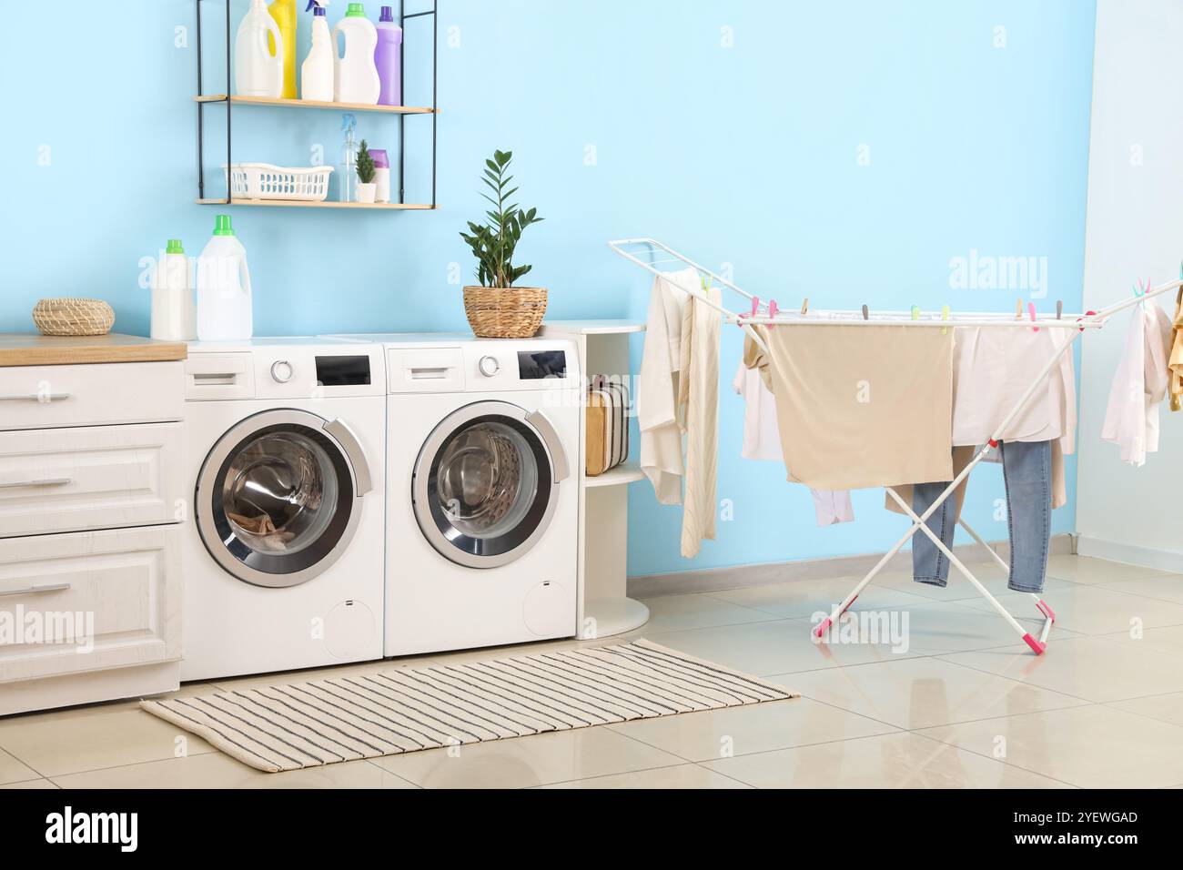Interior of modern laundry room with washing machines and clean clothes ...