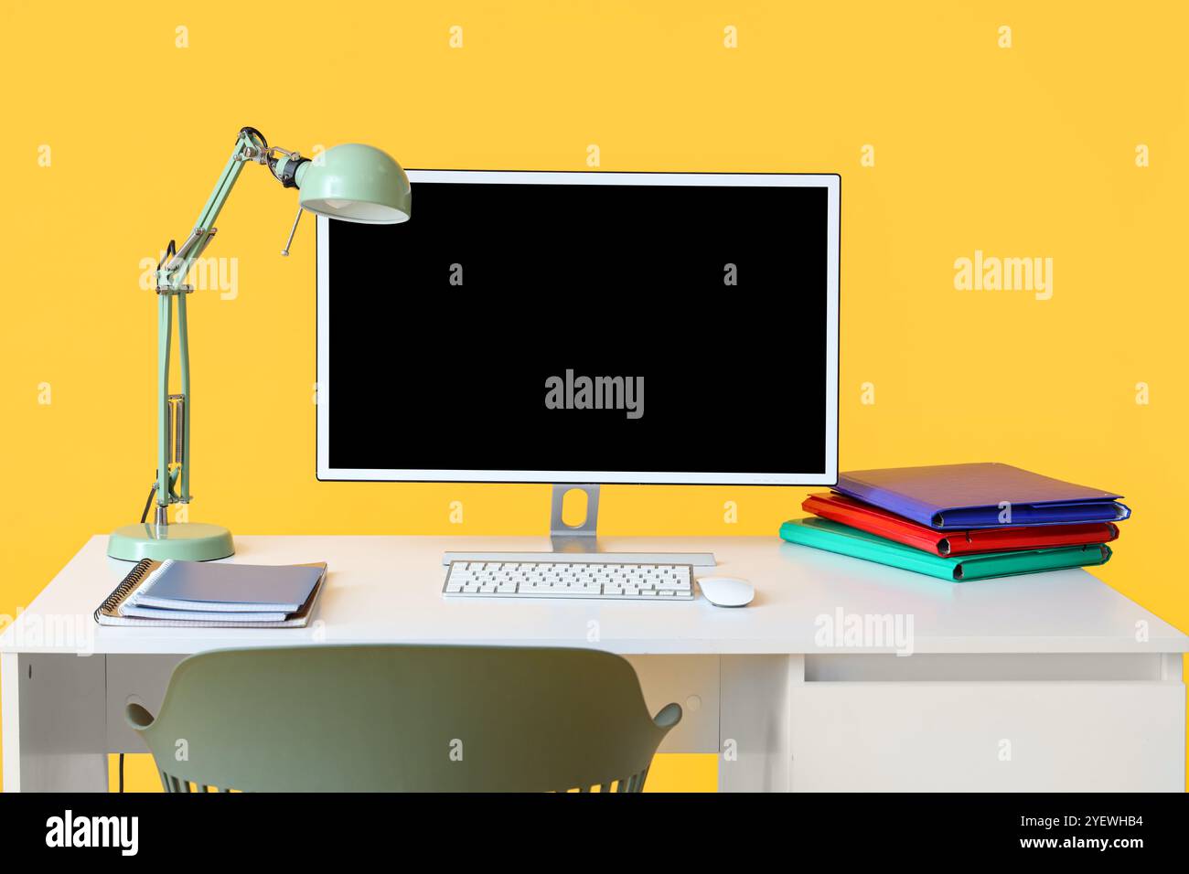 Comfortable table with modern computer, lamp and folders on yellow ...