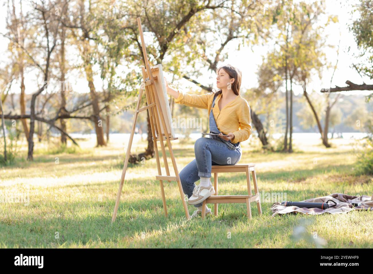 Female artist with palette painting on canvas in park Stock Photo - Alamy